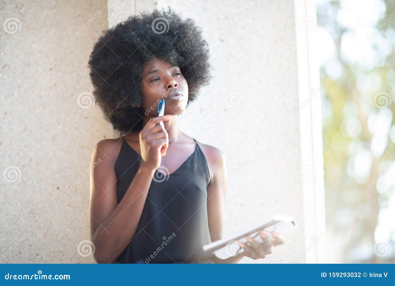 African American Lady Writing Notes Leaning on a Wall of a Concrete ...