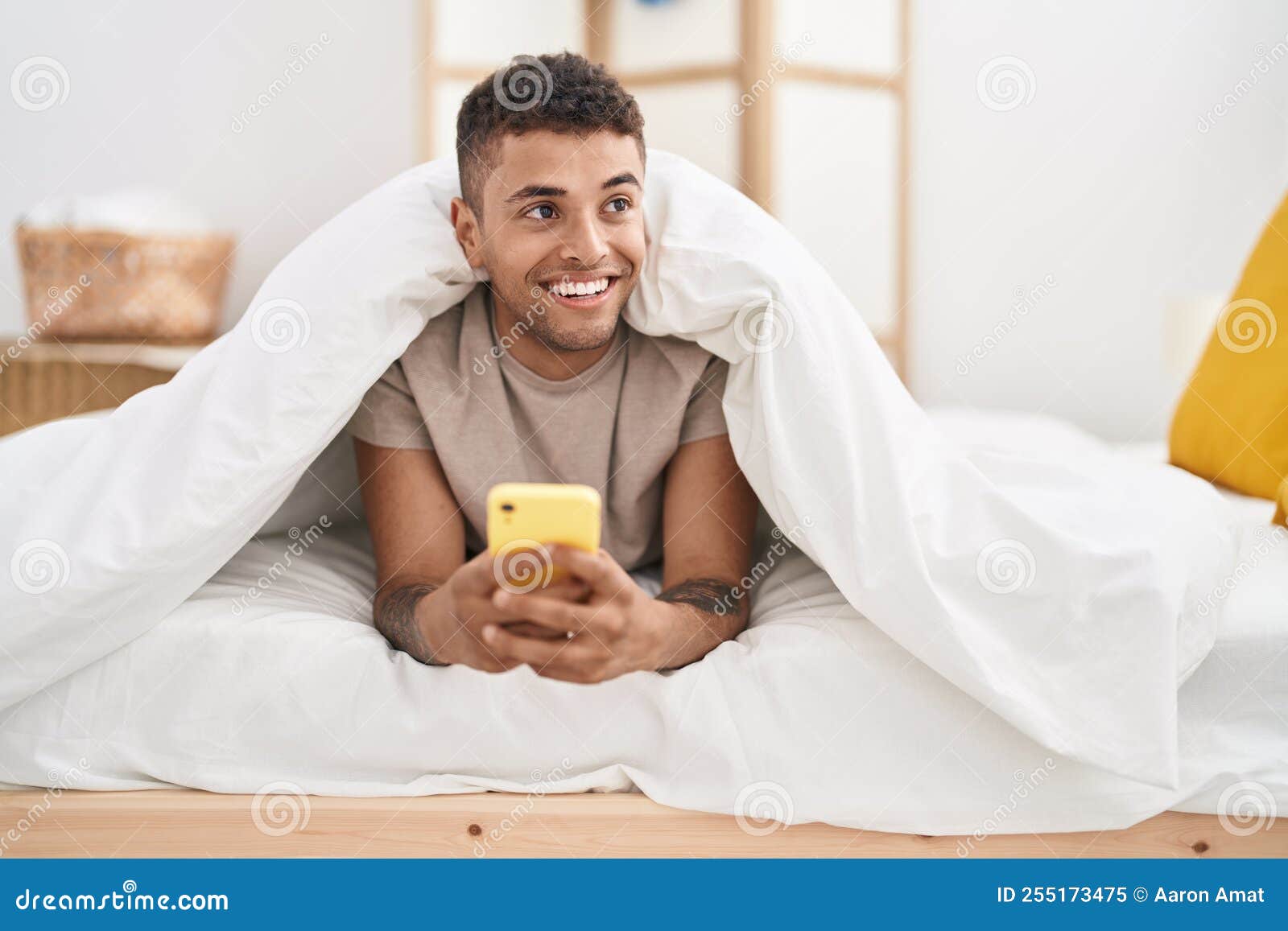 African American Man Using Smartphone Lying on Bed at Bedroom Stock ...