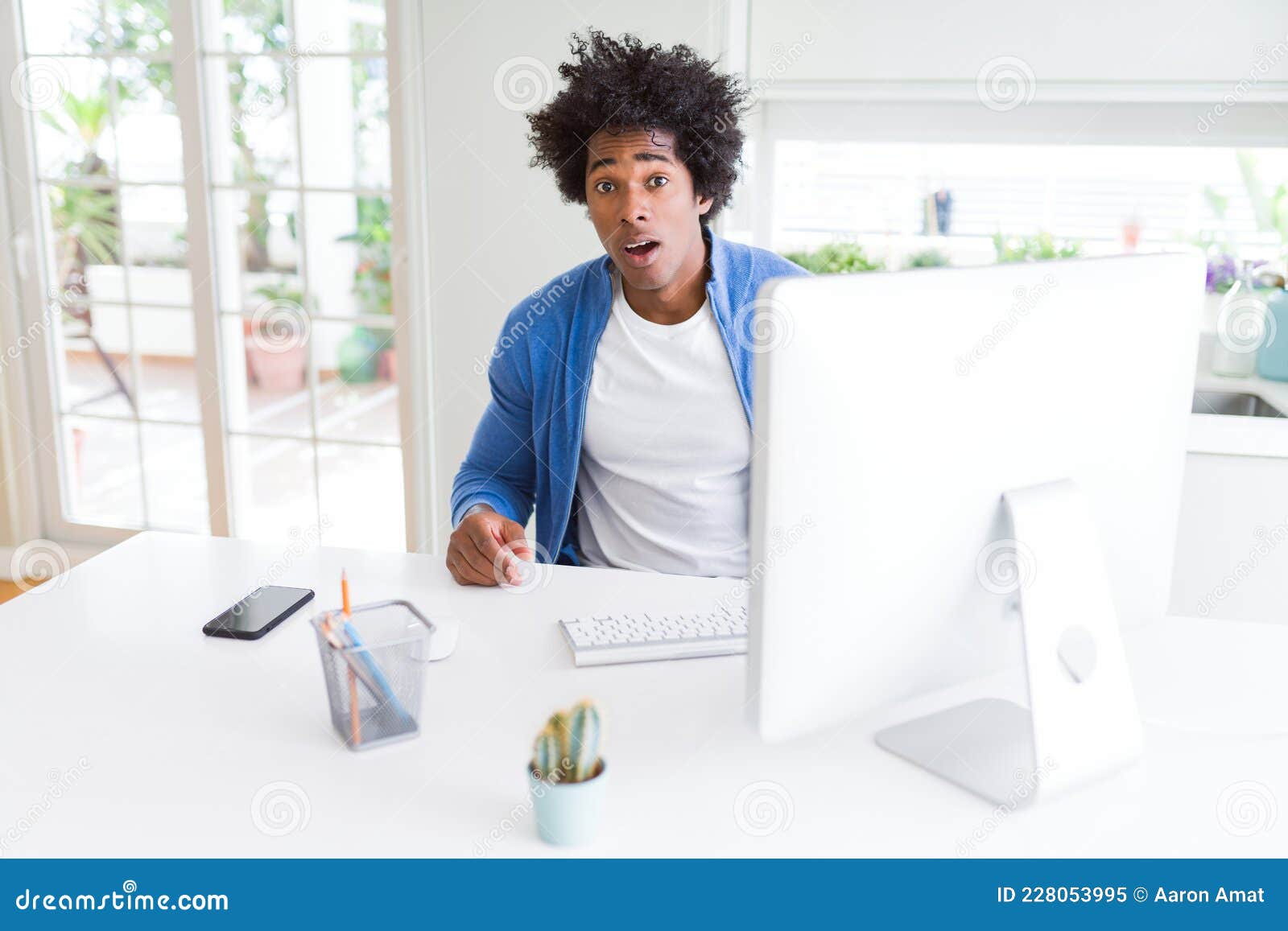 African American Man Working Using Computer Afraid and Shocked with ...