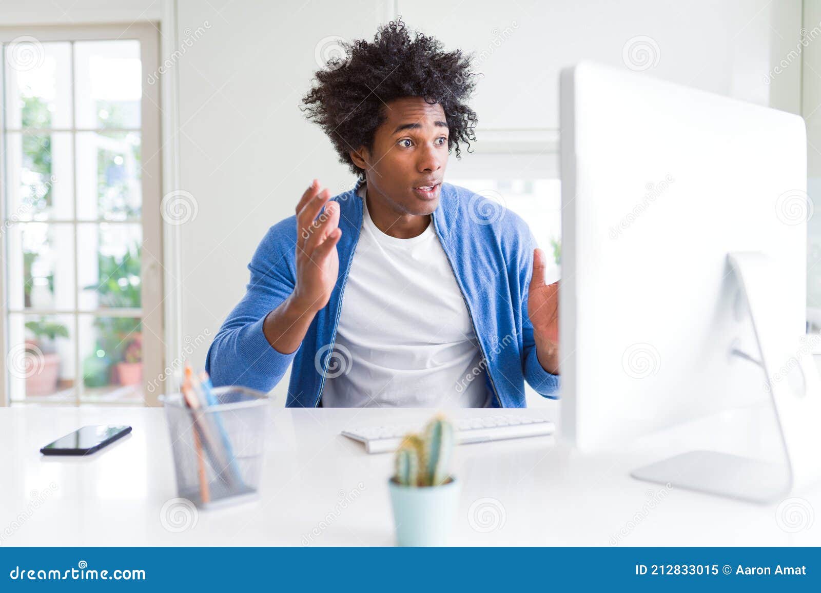African American Man Working Using Computer Scared in Shock with a ...