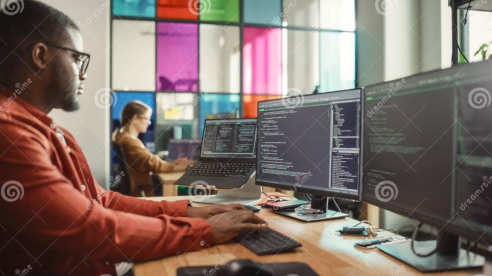 African American Man Writing Code on Desktop Computer with Multiple ...