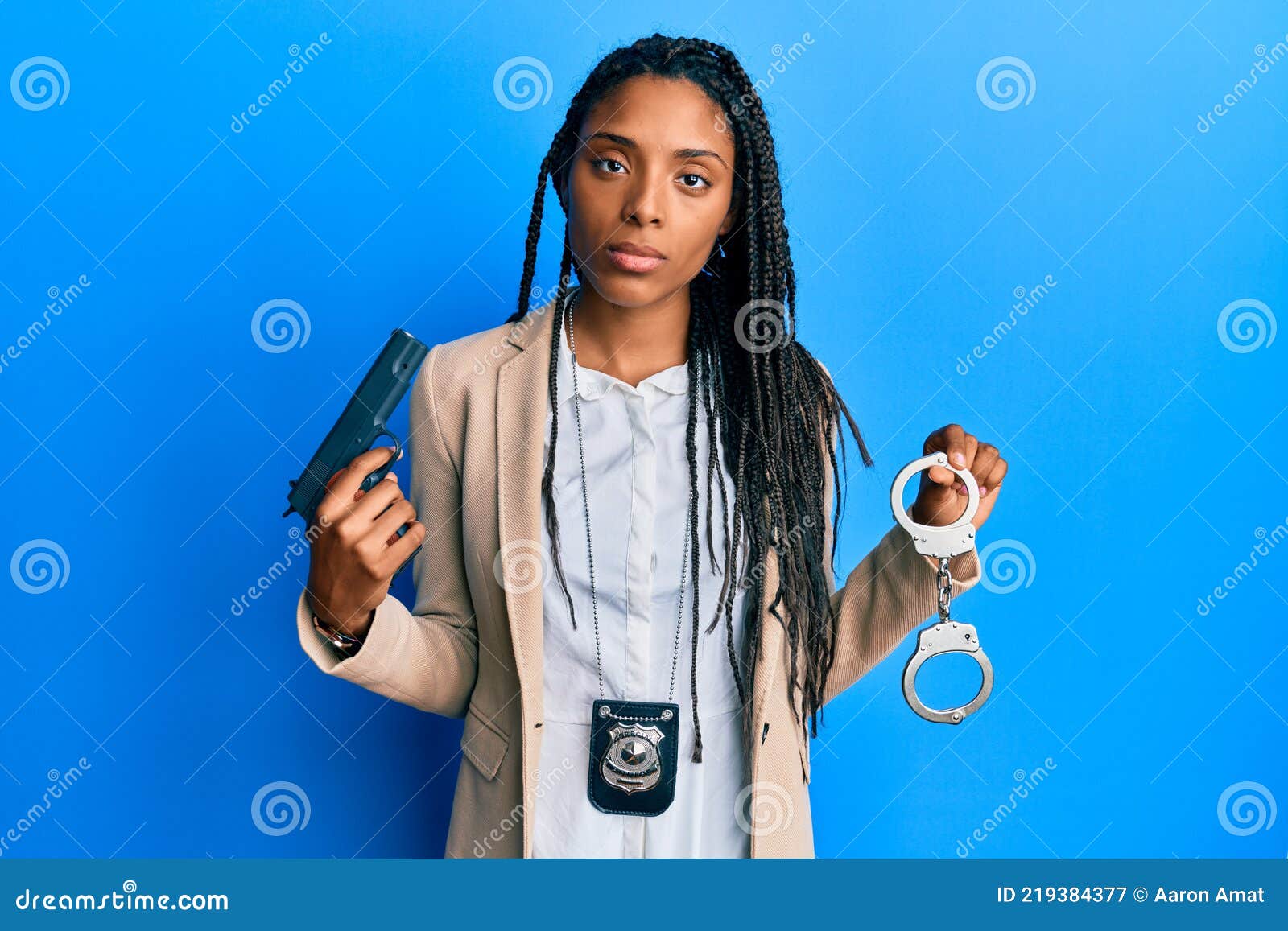 African American Police Woman Holding Gun And Handcuffs Relaxed With