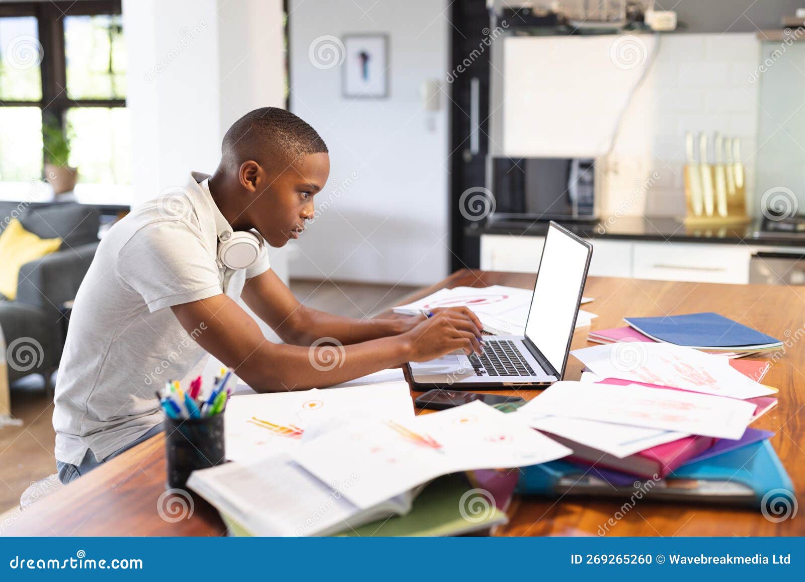 African American Teenage Boy Using Computer and Doing Lessons at Home ...