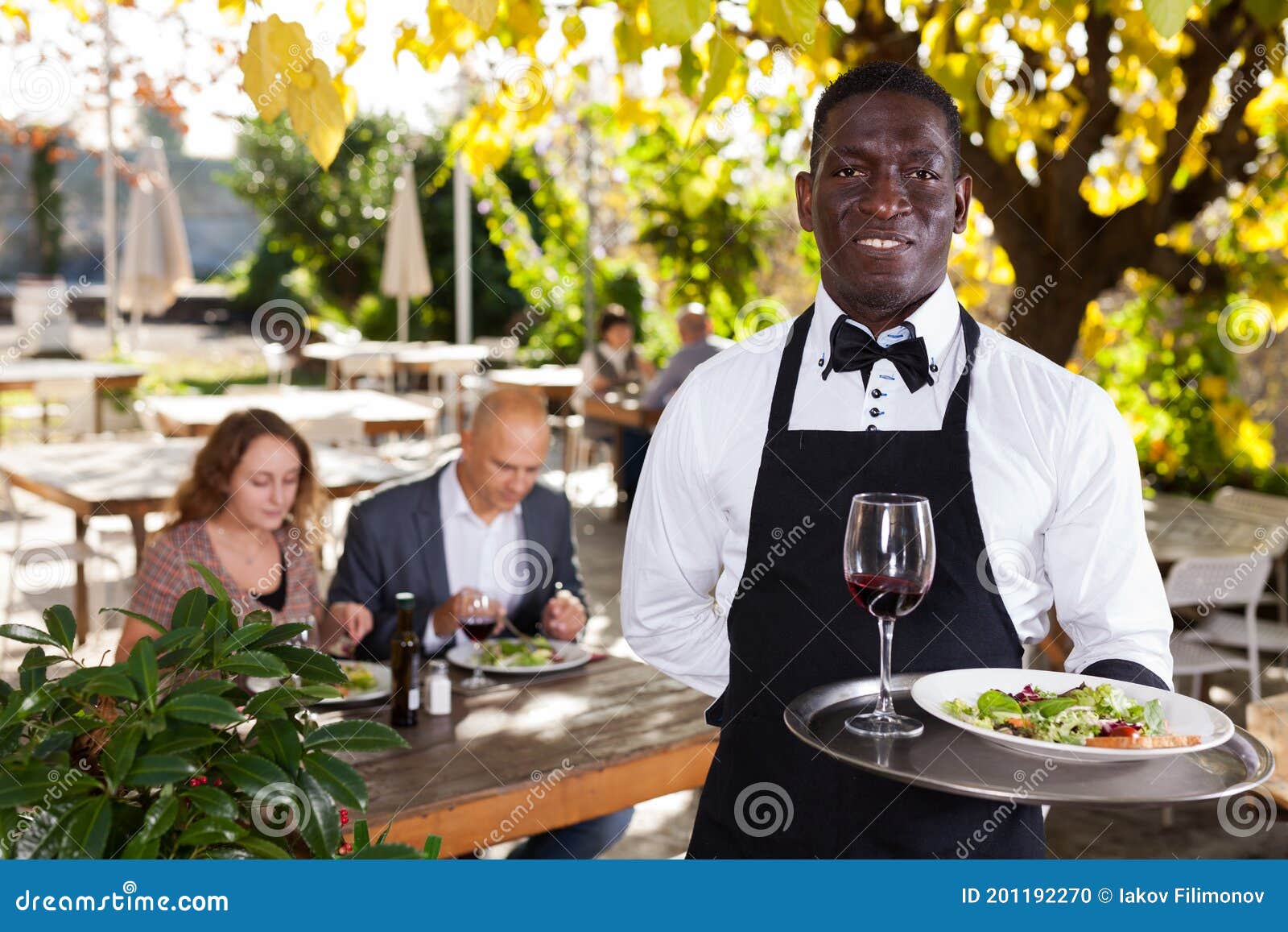 African American Waiter Who Is Standing With Order At Summer Cafe Stock