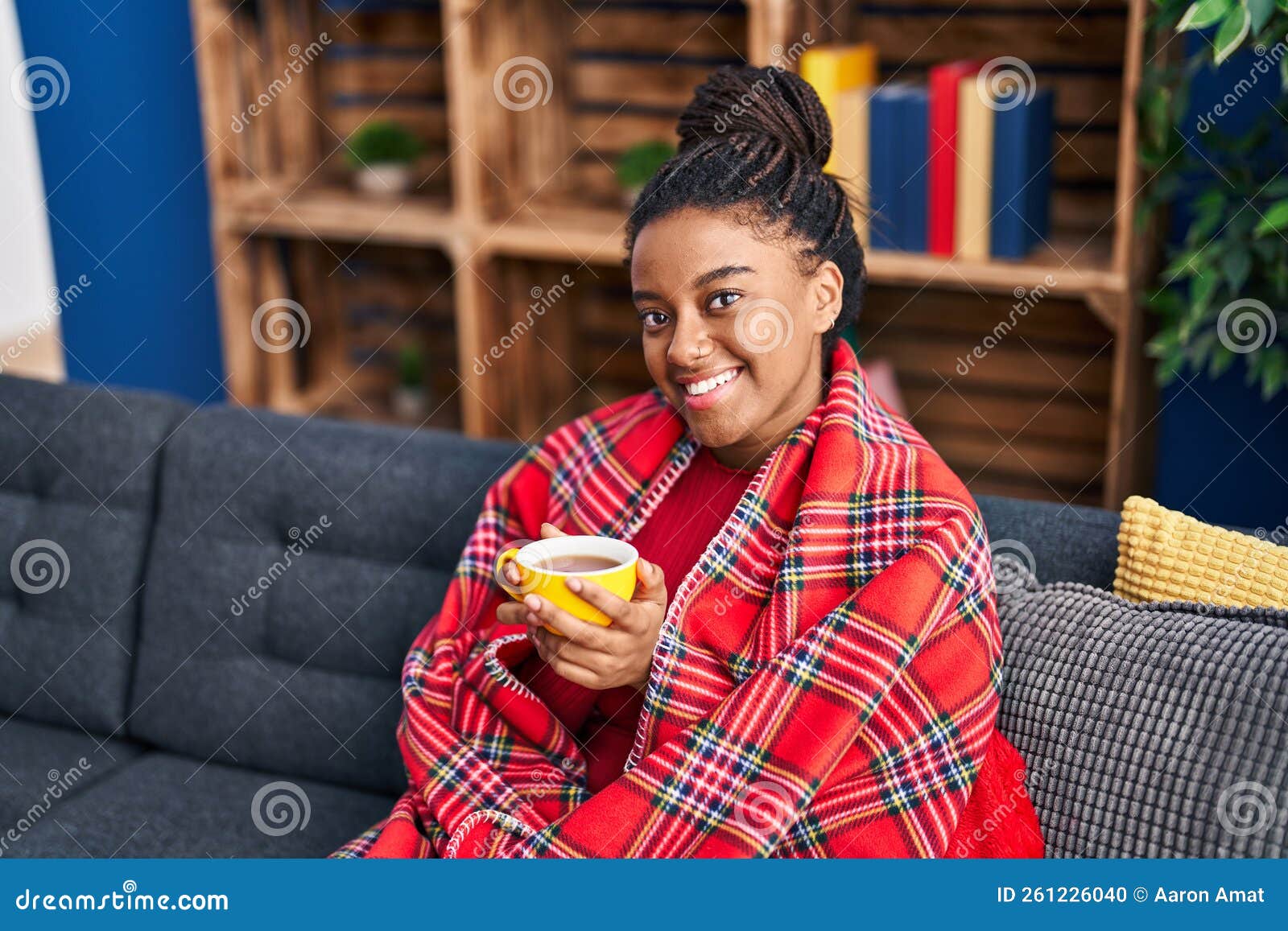 African American Woman Drinking Coffee Sitting On Sofa At Home Stock