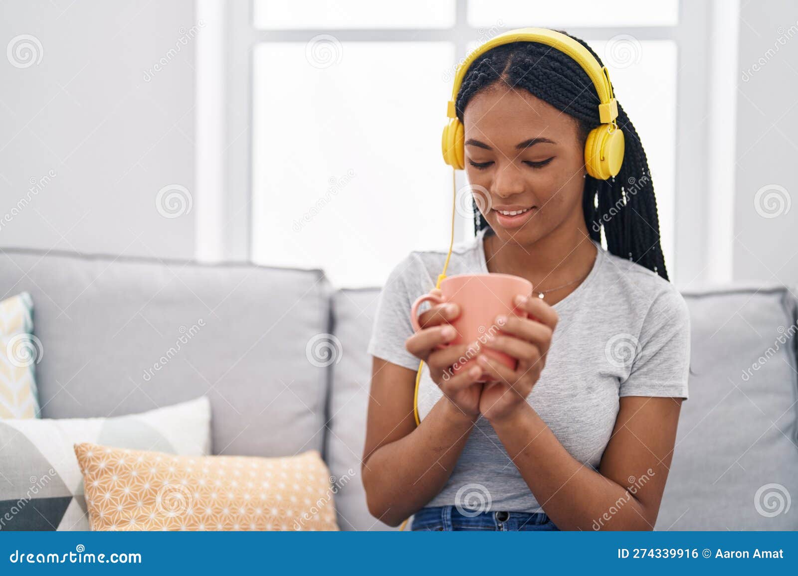 African American Woman Drinking Coffee Sitting On Sofa At Home Stock