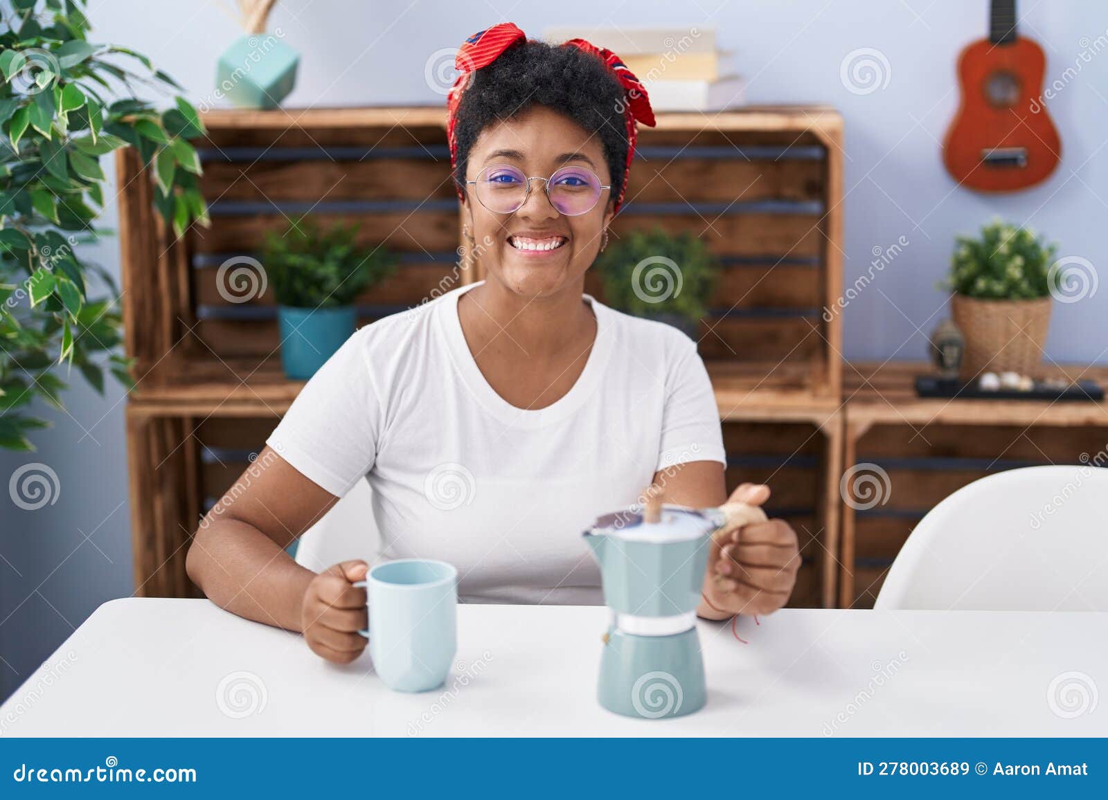 African American Woman Drinking Coffee Sitting On Table At Home Stock