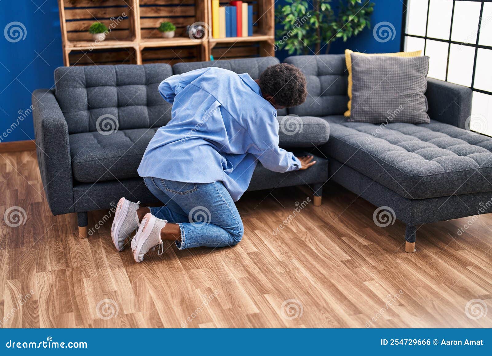 African American Woman Looking for Under Sofa at Home Stock Photo ...