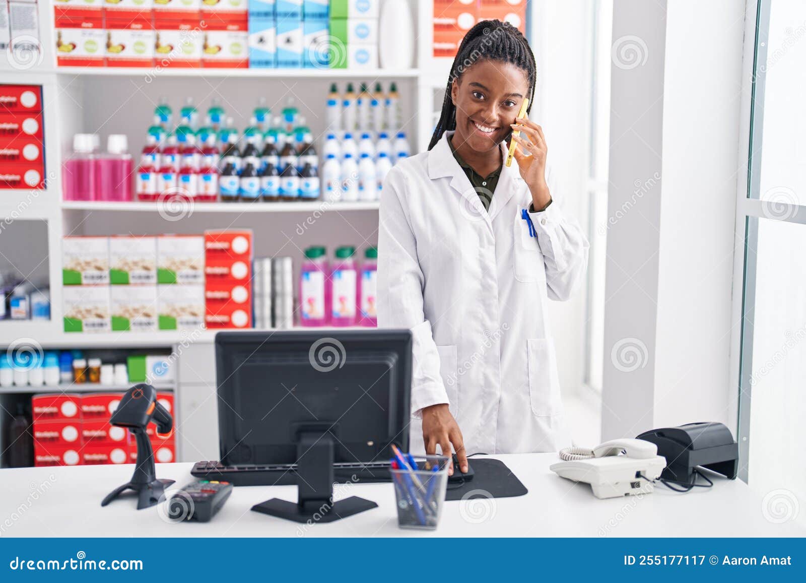 African American Woman Pharmacist Talking on Smartphone Using Computer ...