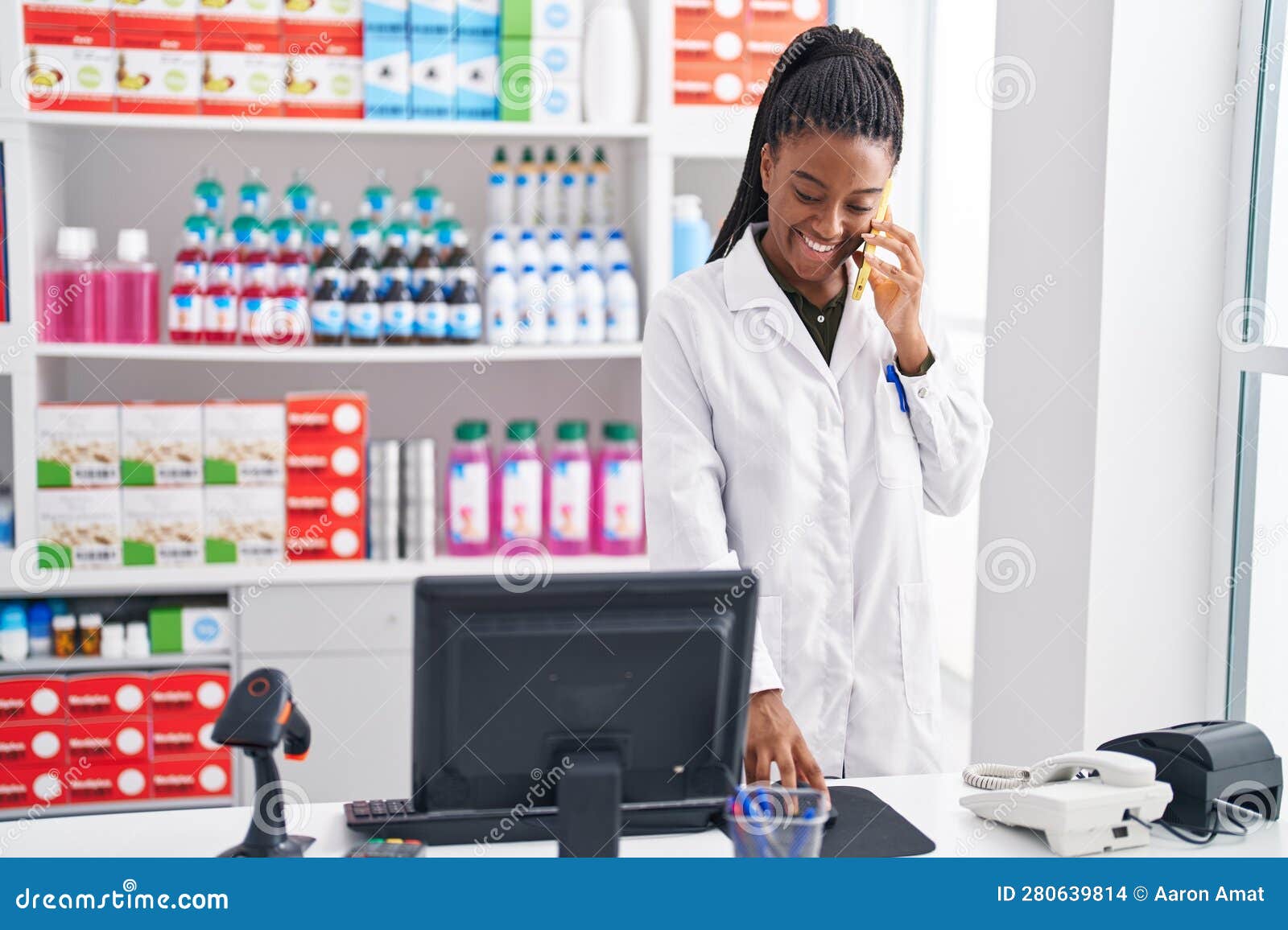 African American Woman Pharmacist Talking on Smartphone Using Computer ...