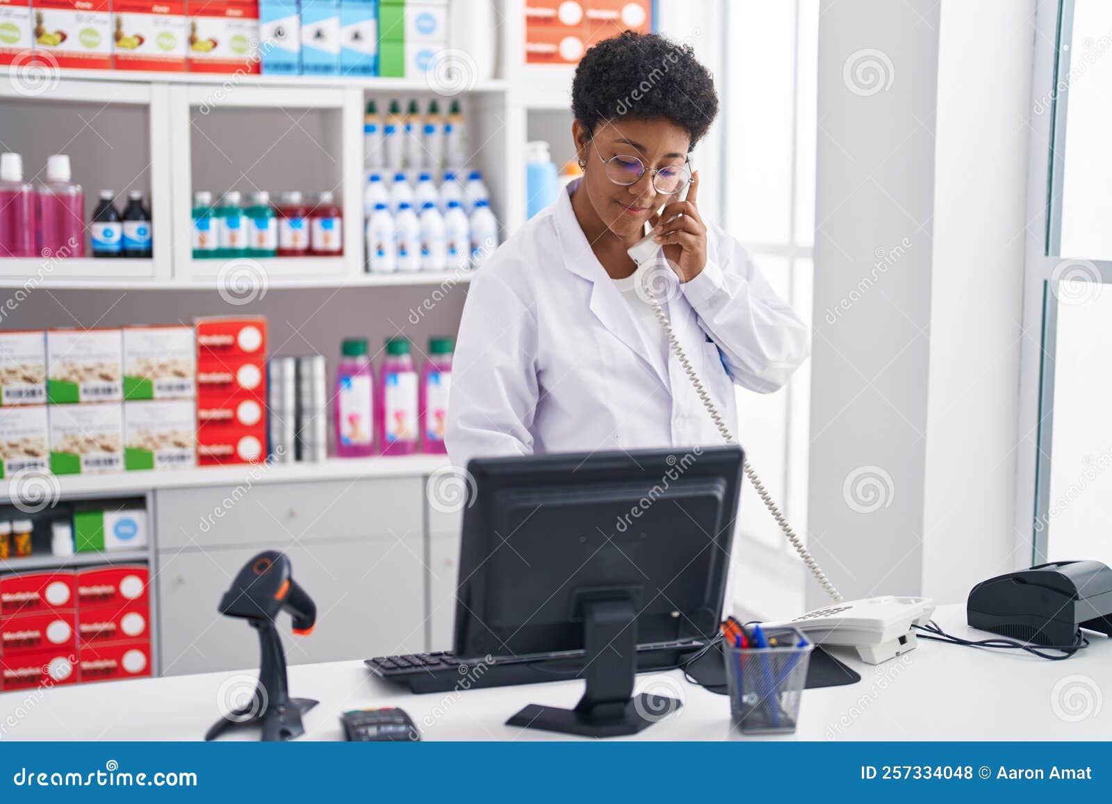 African American Woman Pharmacist Using Computer Talking on Telephone ...