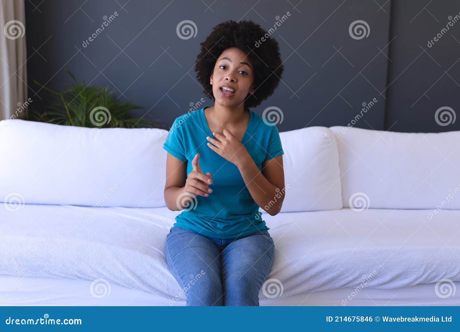 African American Woman Sitting On Sofa Making A Video Call And Smiling