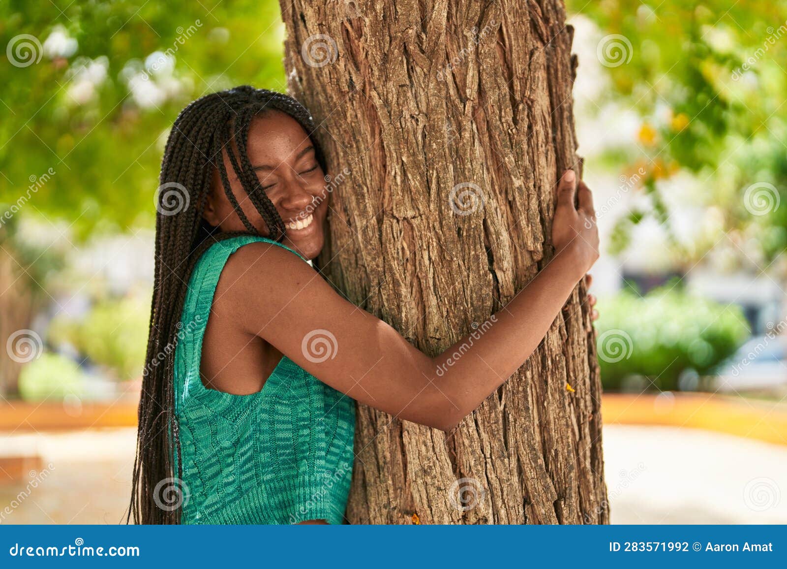 African American Woman Smiling Confident Hugging Tree at Park Stock ...