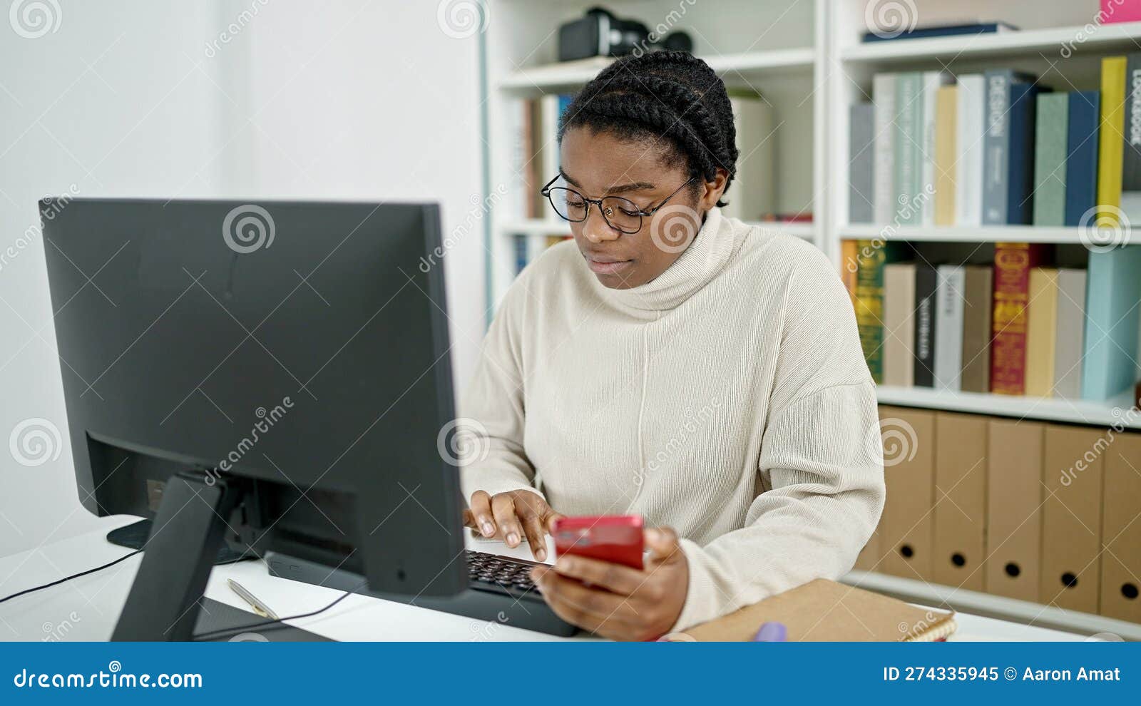 African American Woman Student Using Computer and Smartphone at Library ...