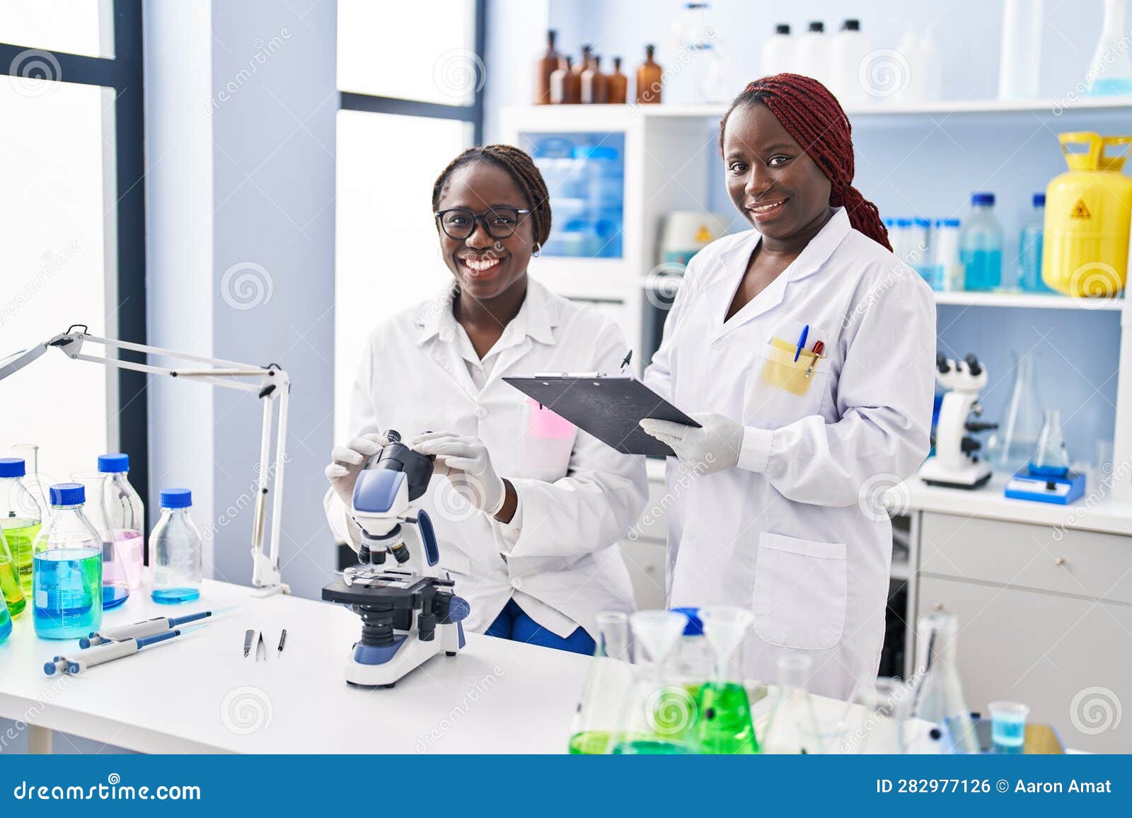 African American Women Scientists Using Microscope Writing on Document ...
