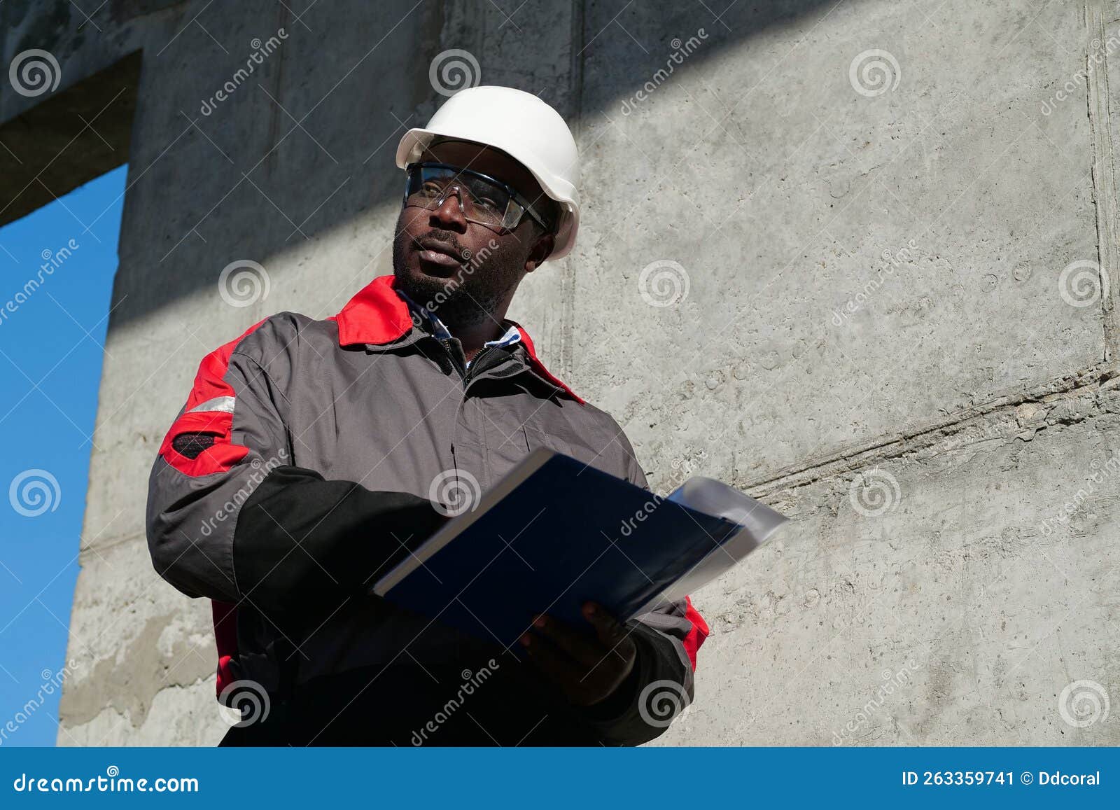 African American Workman Stands at Construction Site with Work Papers ...