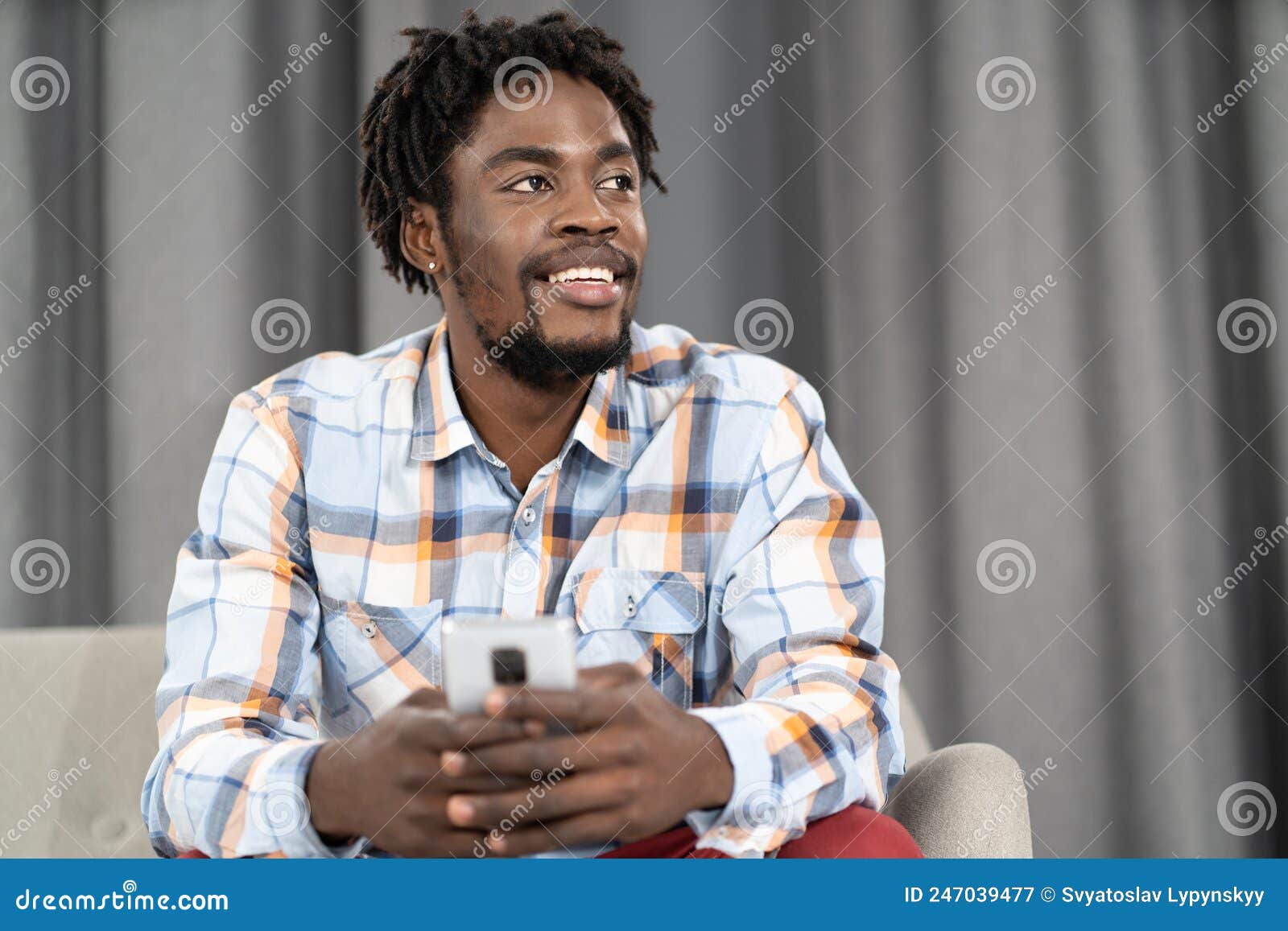 African American Young Man Holding Phone or Smartphone in Hand Looking ... African American Young Man Holding Phone or Smartphone in Hand Looking ...