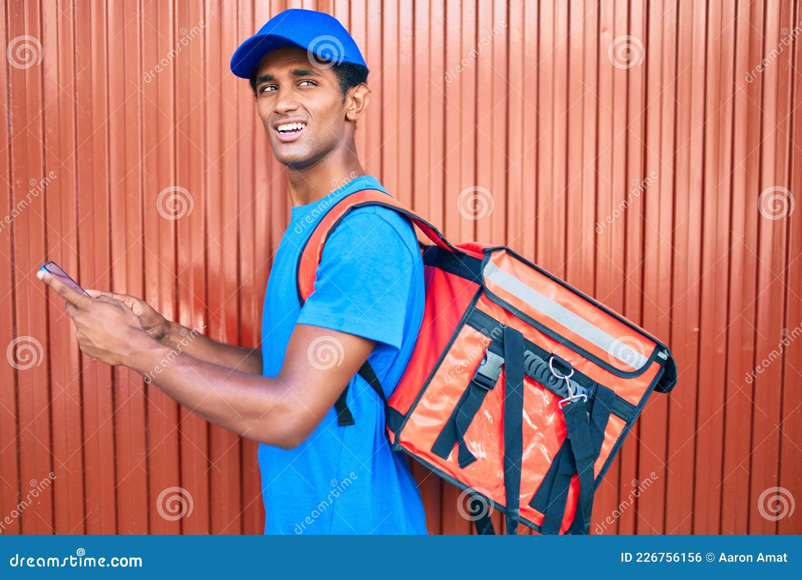 African Delivery Man Wearing Courier Uniform Outdoors Using Smartphone ...