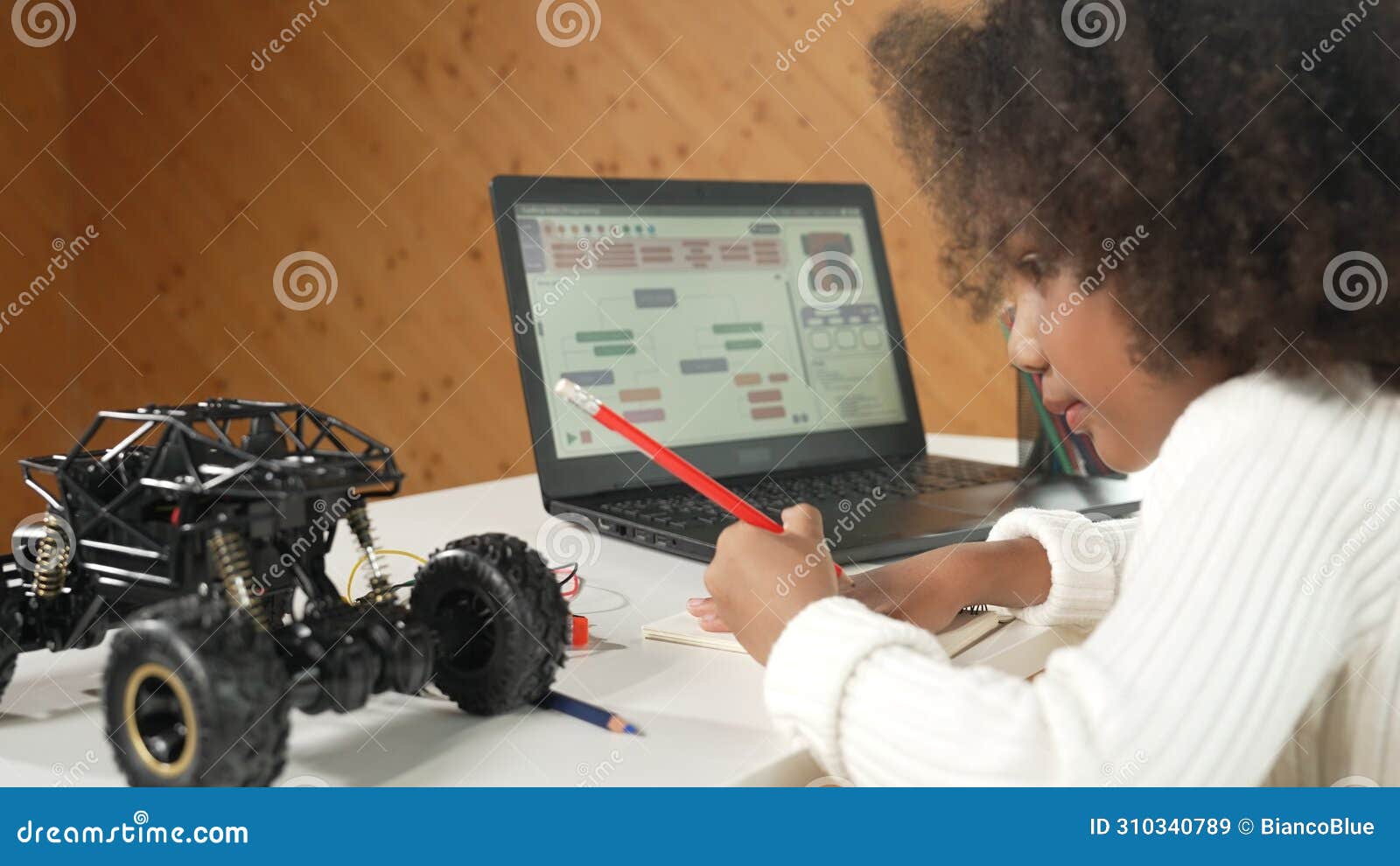 African Kid Writing Car Model Structure while Laptop Display Code ...