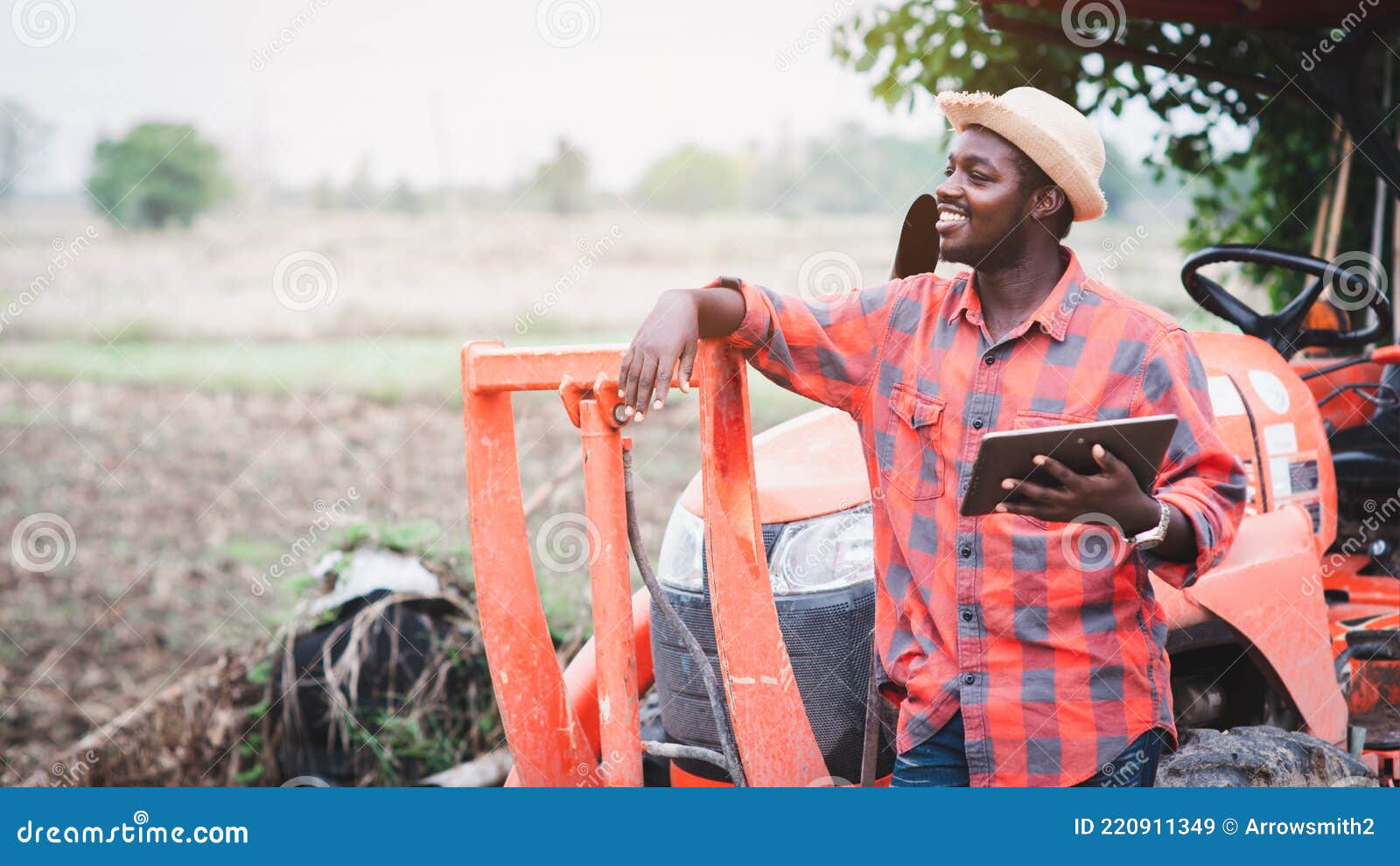 African Man Farmer Working in the Field with a Tractor and Using Tablet ...