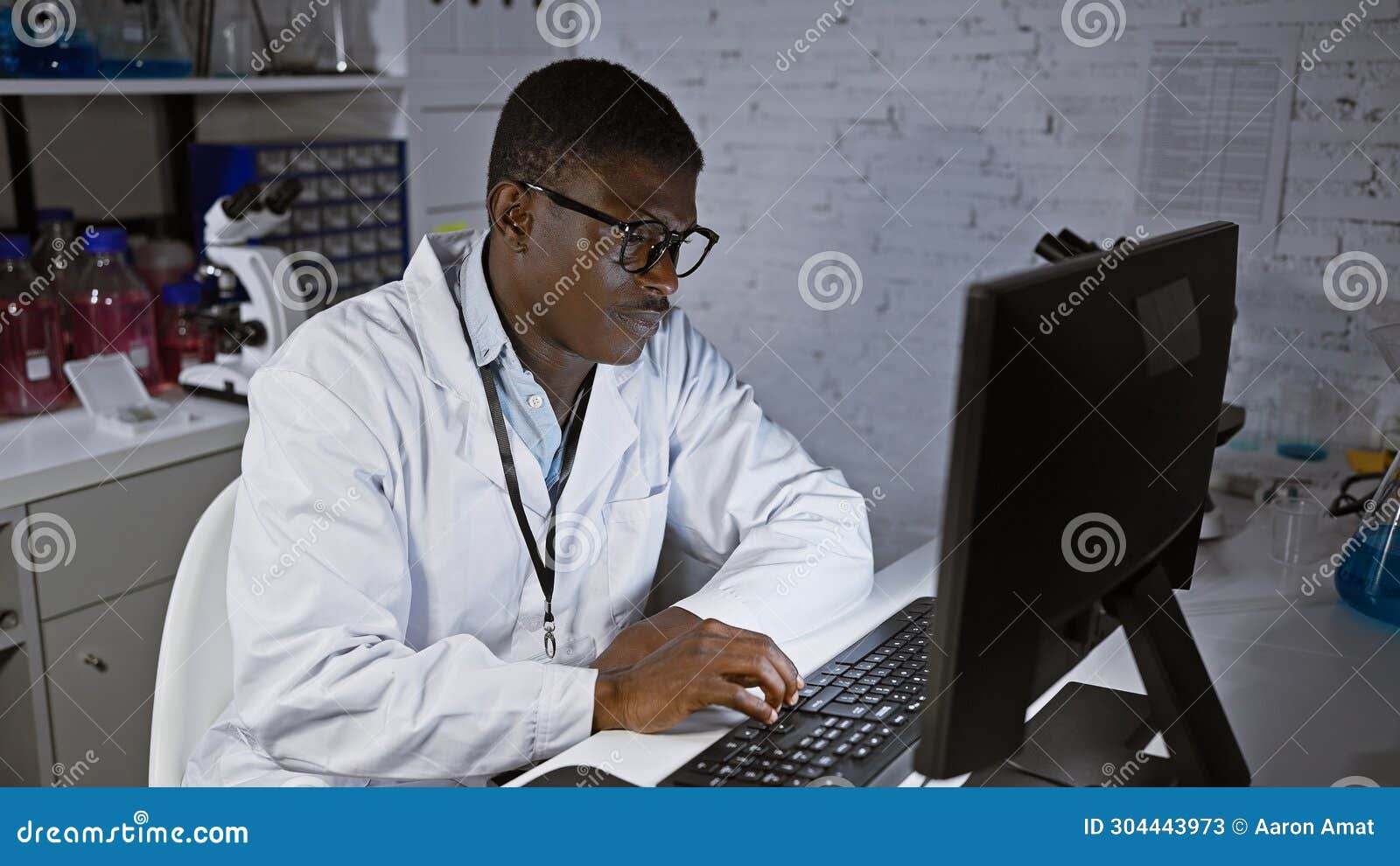 African Man in Lab Coat Working on Computer in a Laboratory Setting ...