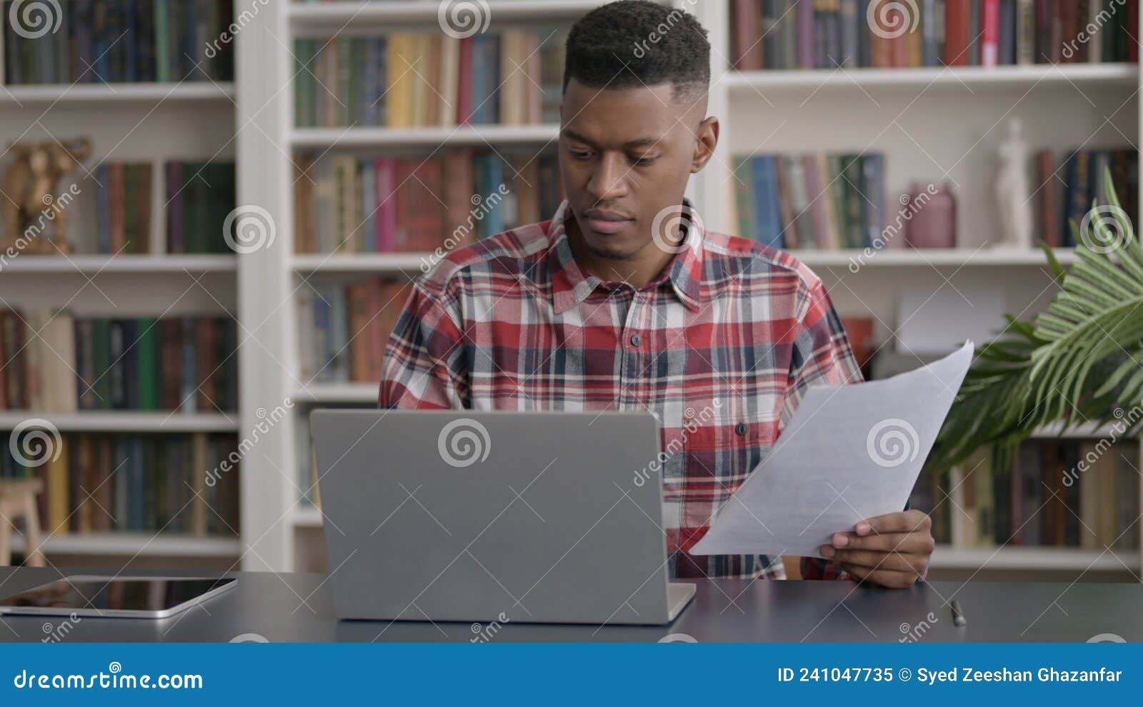 African Man with Laptop Reading Documents in Office Stock Image - Image ...