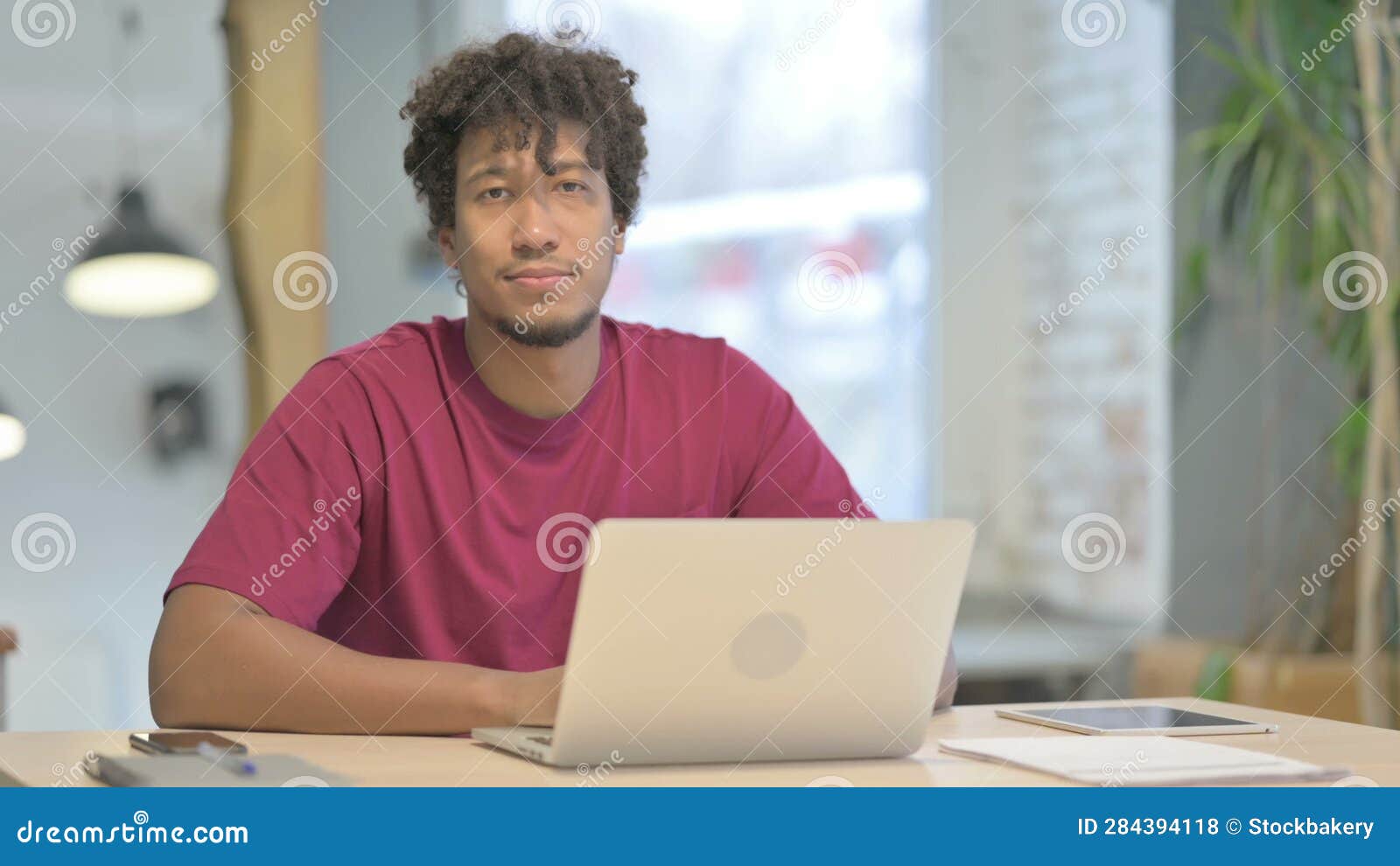 African Man Looking at Camera while Using Laptop Stock Footage - Video ...
