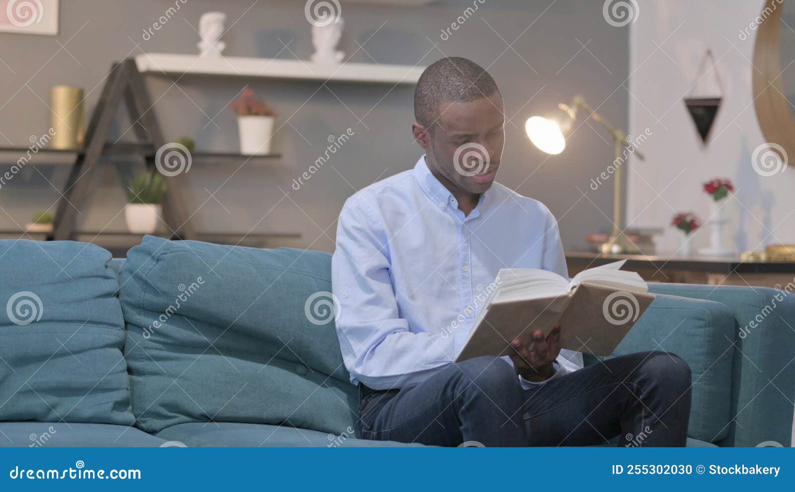 African Man Reading Book while Sitting on Sofa Stock Photo - Image of ...