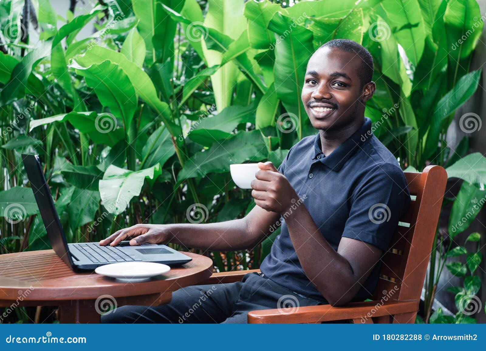 African Man Using a Laptop Computer at Home with Holding a Cup of ...