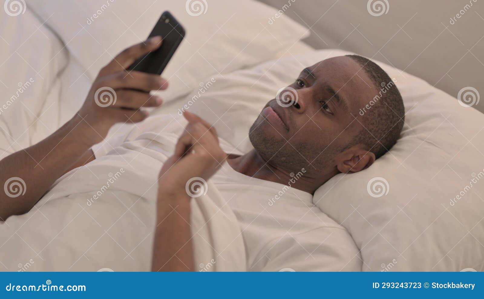 African Man Using Smartphone while Lying in Bed Stock Video - Video of ...