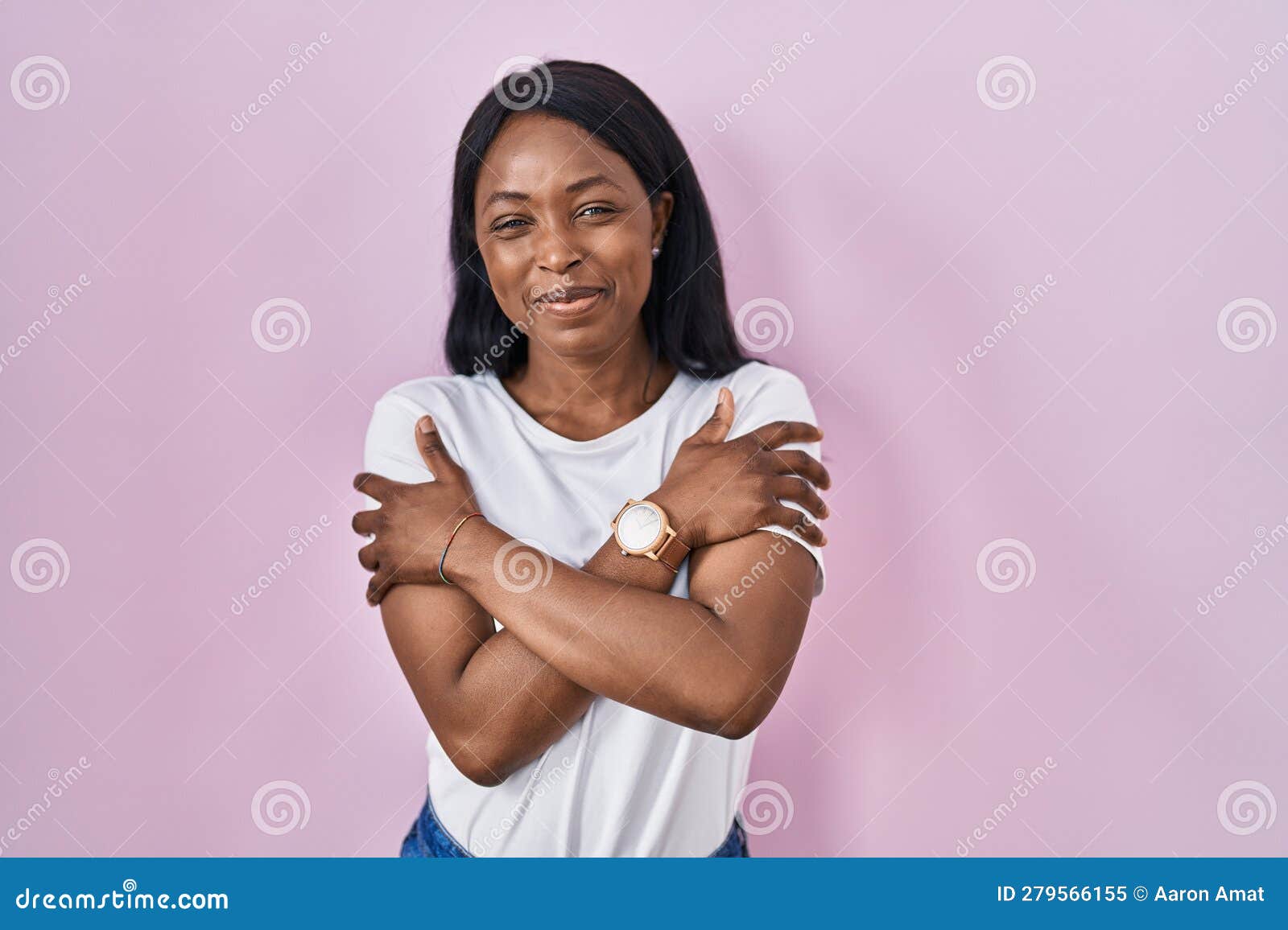 African Young Woman Wearing Casual White T Shirt Hugging Oneself Happy
