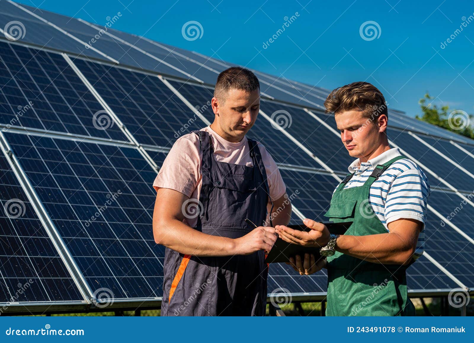 Against the Background of Solar Panels, Two Workers Write in a Tablet ...
