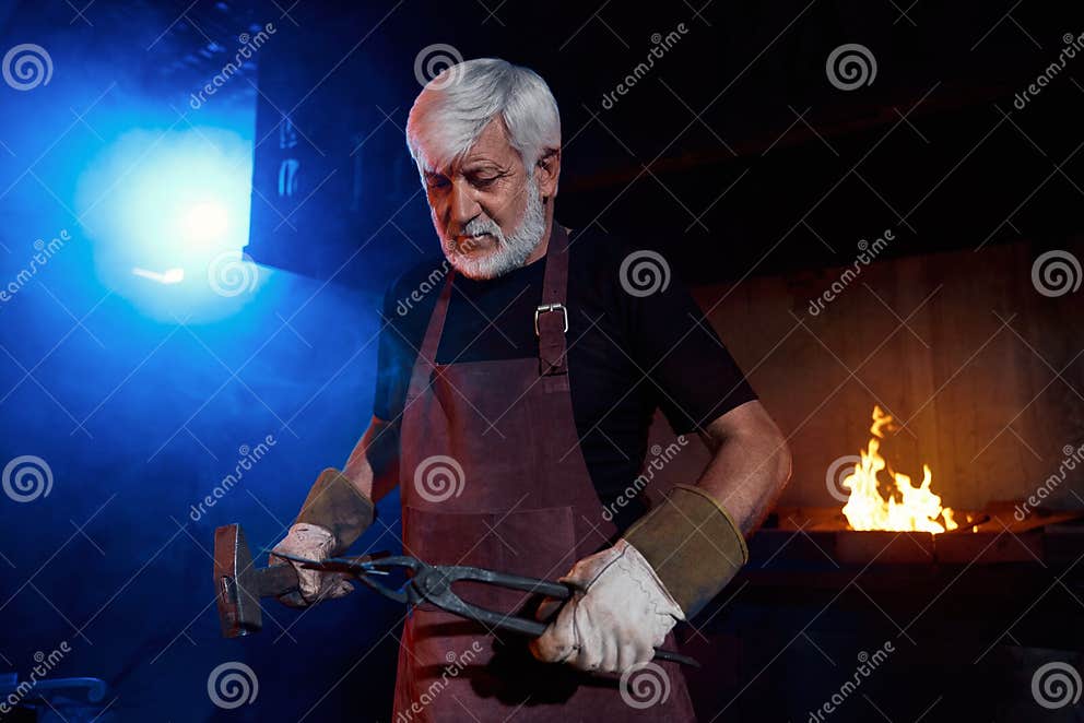 Aged Blacksmith Using Hammer and Forceps for Work with Metal Stock ...