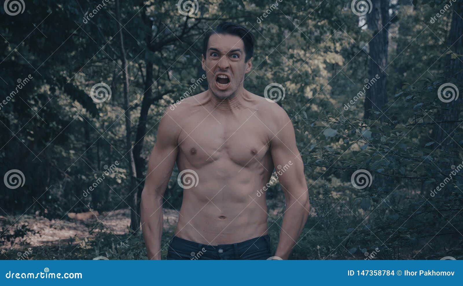 Agressive Man with a Naked Torso Furiously Screaming in the Forest ...