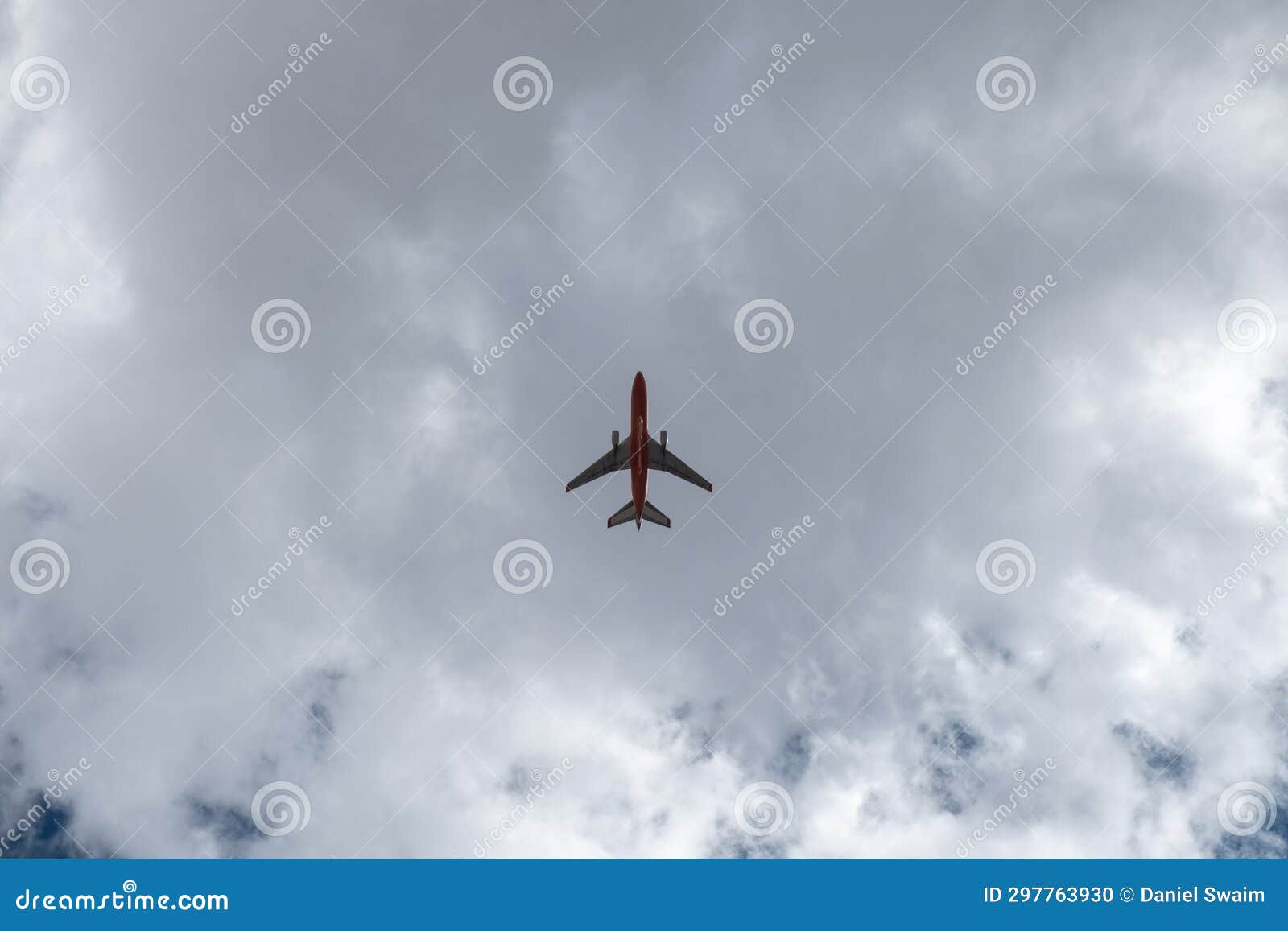 An Airplane Flies Directly Overhead, Outlined Against a Cloudy Sky ...