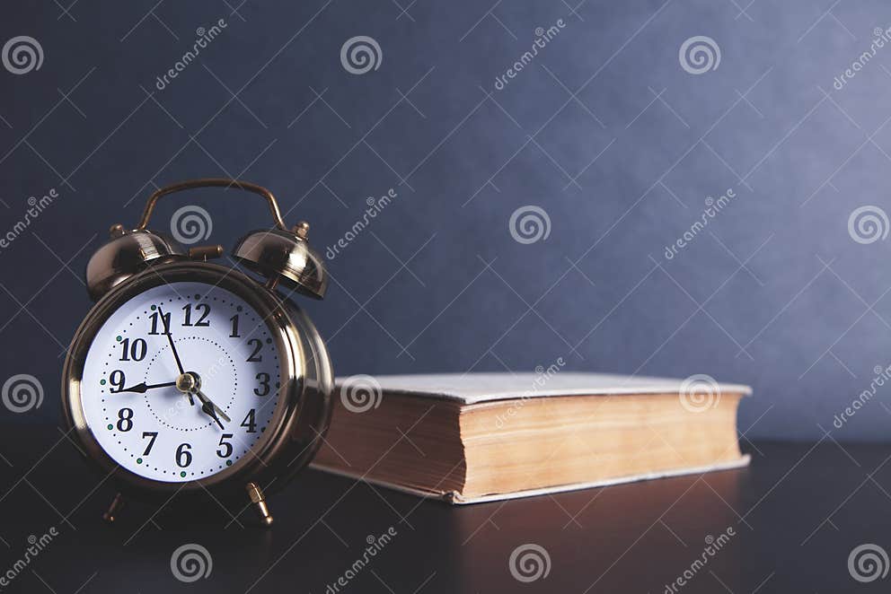 Alarm clock a book stock image. Image of time, closeup - 135178093