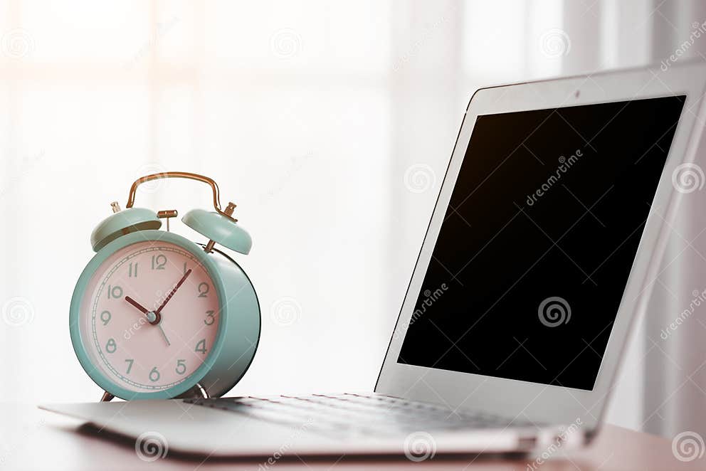 An Alarm Clock with a Computer Laptop on the Table Stock Photo - Image ...