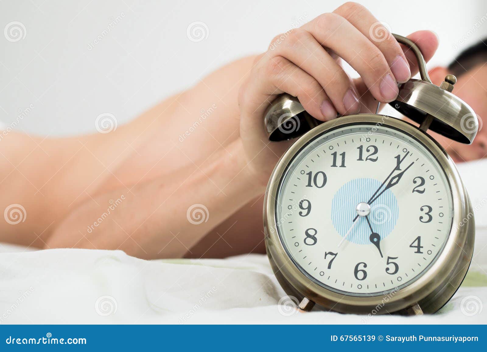 Alarm Clock with Man Waking Up on Bed in Background (Shallow Depth of ...