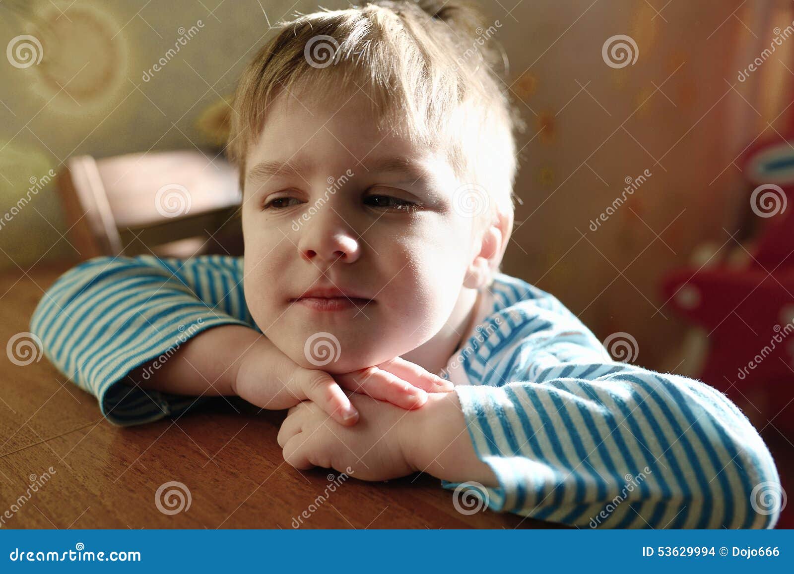 The Amusing Child Sits at a Table and Cunning Looks Stock Photo - Image ...