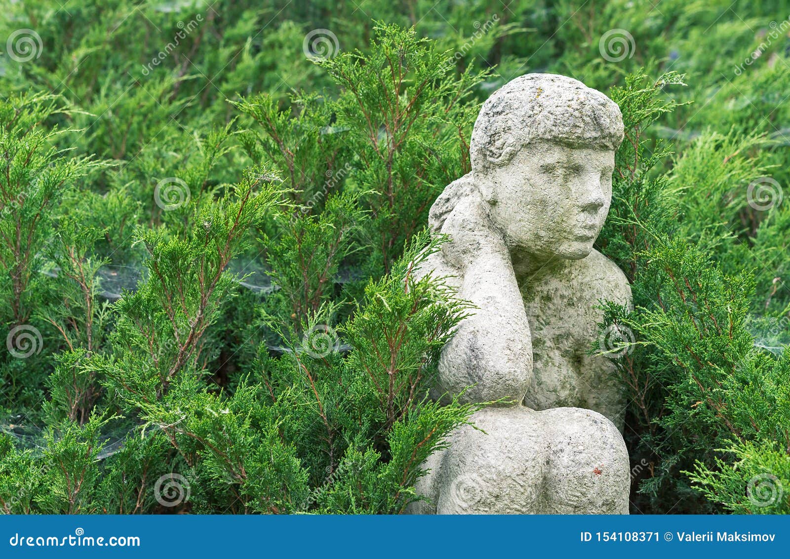 An Ancient Stone Statue of a Sitting Girl among the Green Shrubs Stock ...