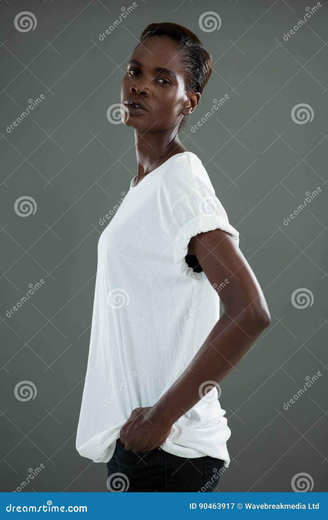 Androgynous Man In White Top Posing Against Grey Background Stock Image ...