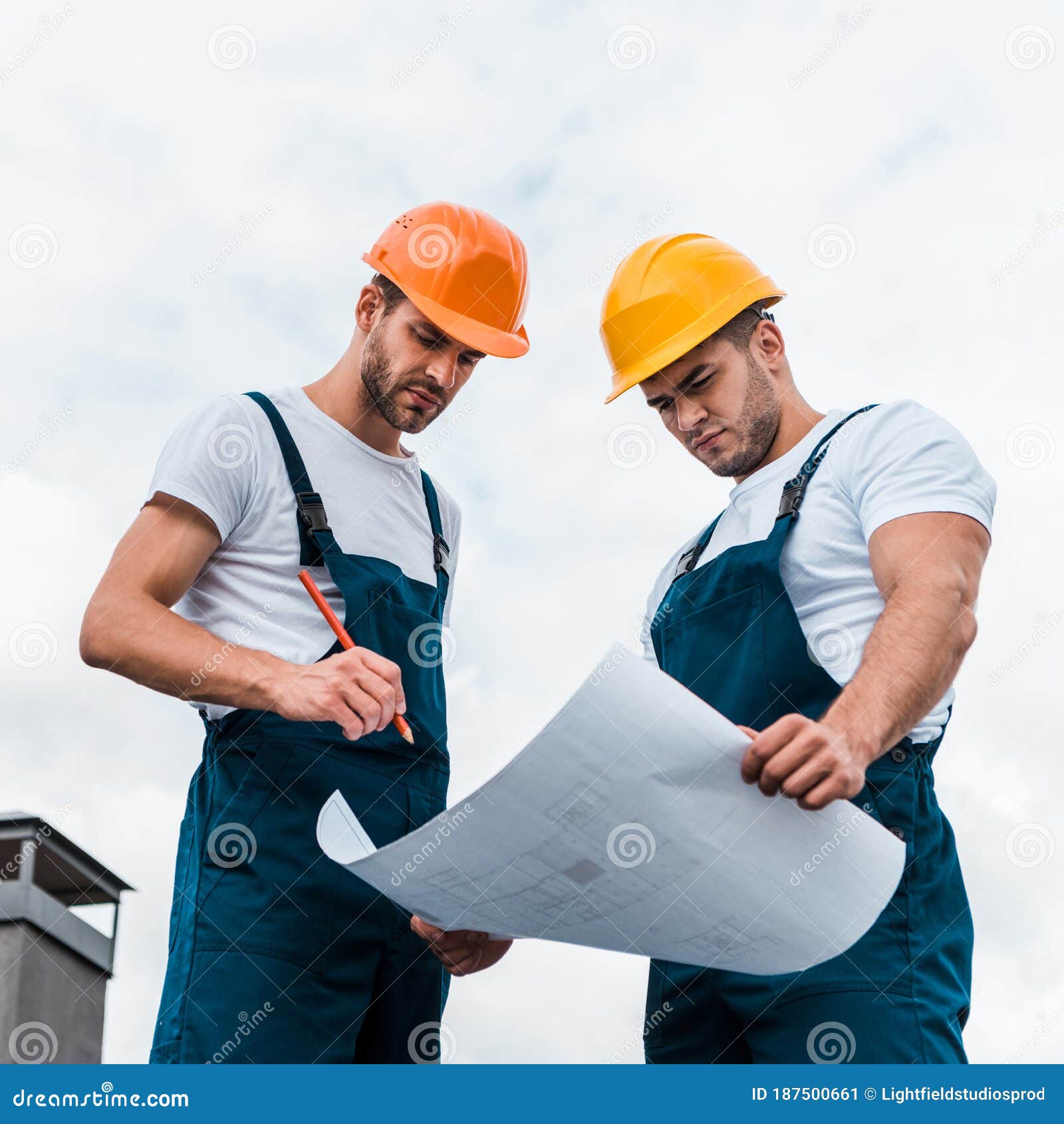 Angle View of Handsome Builders in Uniform Looking at Paper with Plan ...