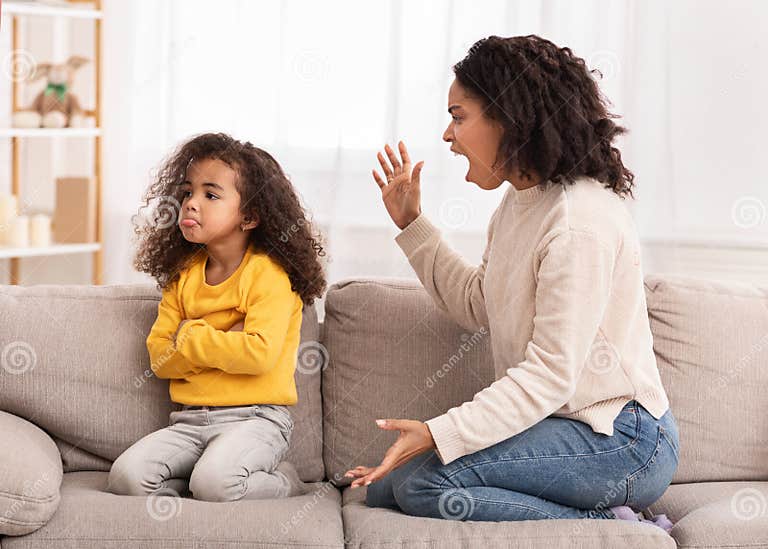 Angry Mother Shouting At Daughter Sitting On Couch At Home Stock Image