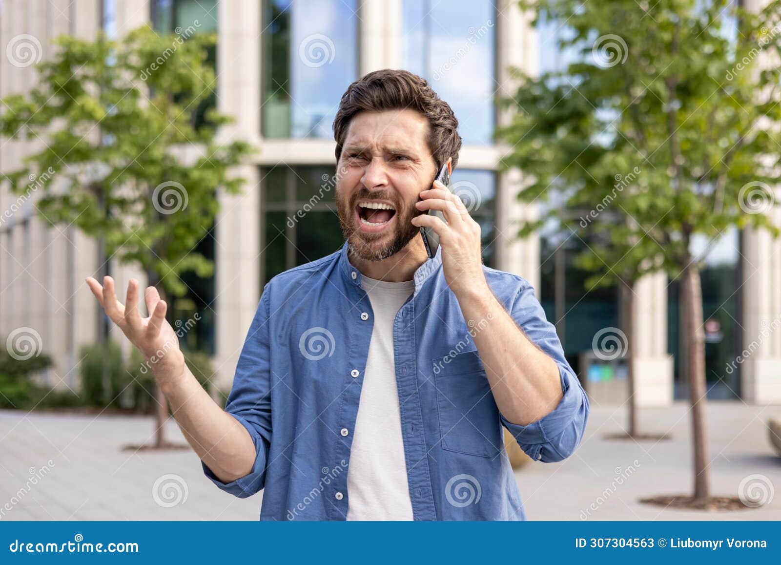 Angry And Frustrated Young Man Emotionally Talking On Mobile Phone On