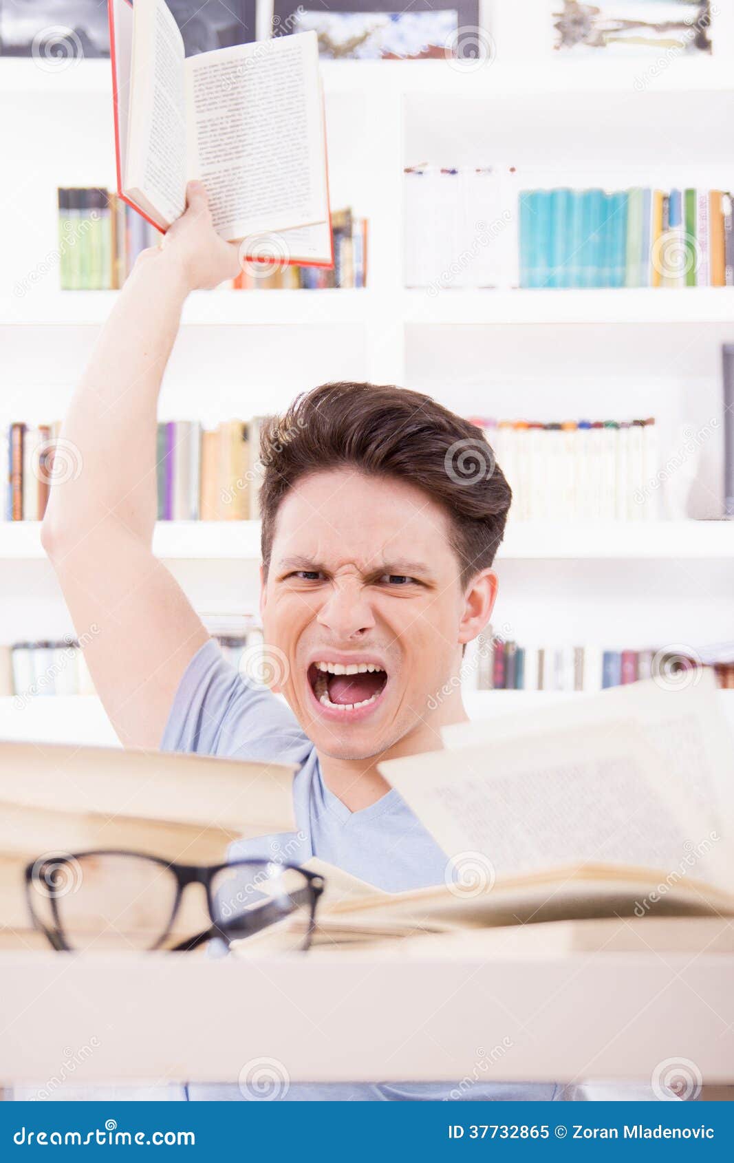 Angry Student with Expression Surrounded by Books Throwing a Bo Stock ...