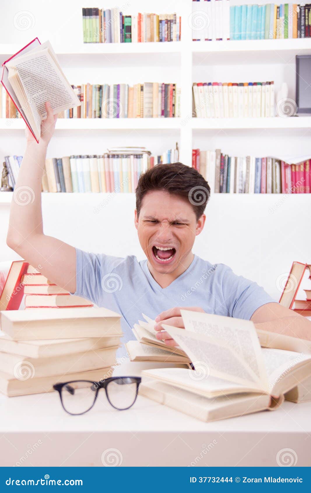Angry Student Surrounded by Books Throws a Book Stock Photo - Image of ...