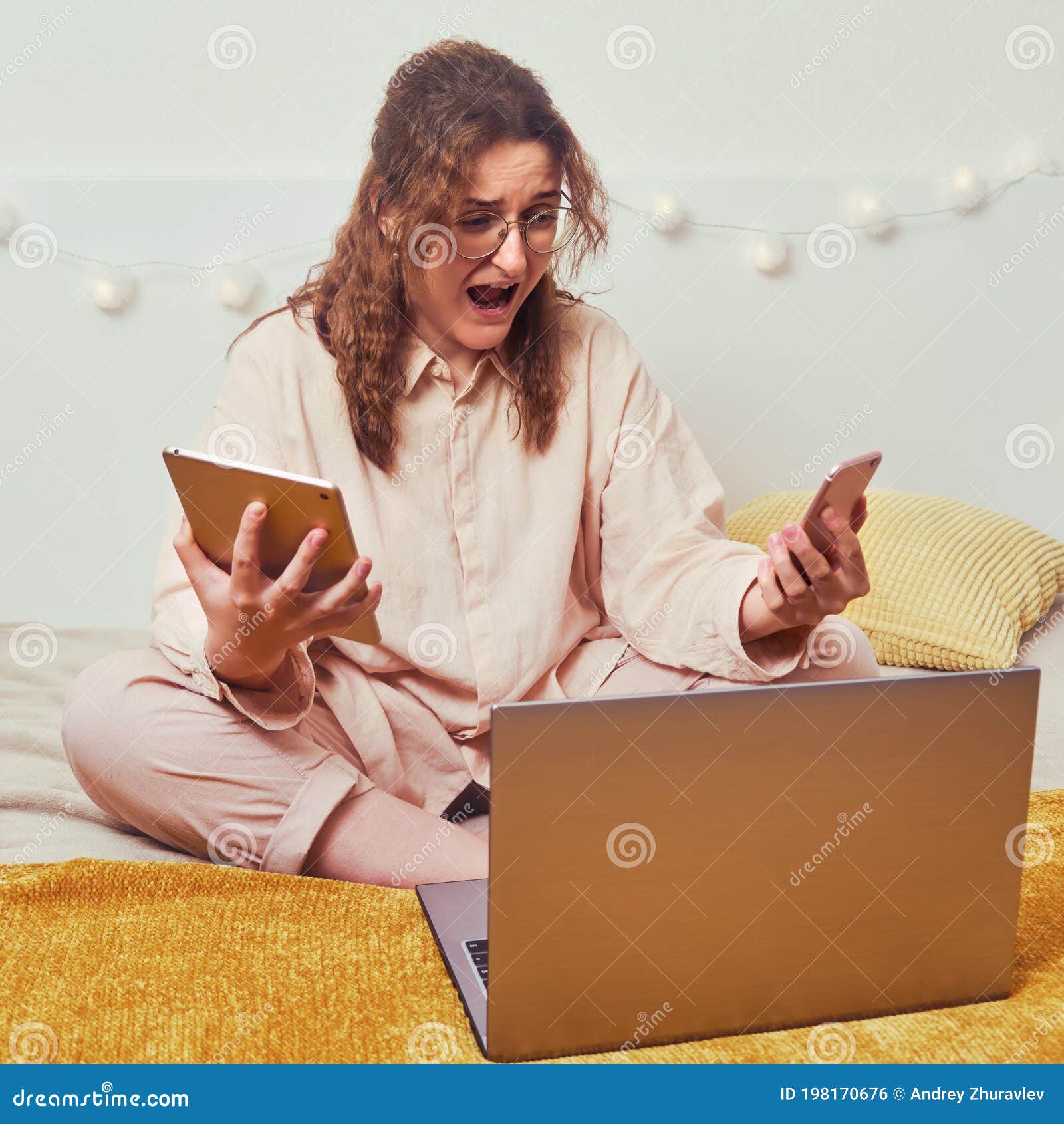 An Angry Woman Screams with Gadgets in Her Hands on a Home Bed ...