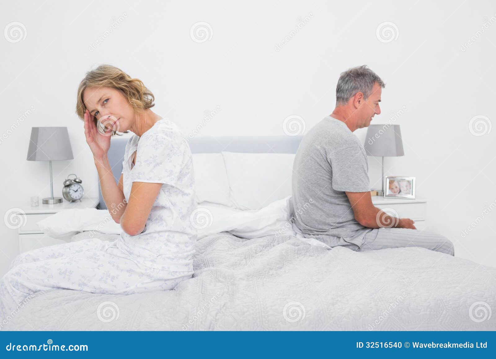 Annoyed Couple Sitting On Different Sides Of Bed Having A Dispute Stock