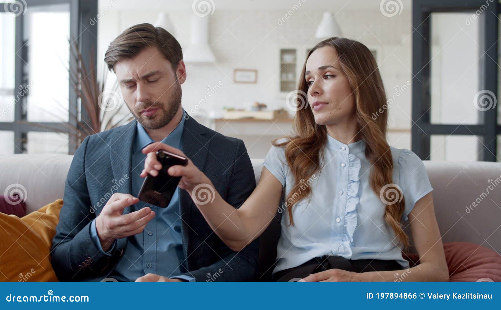 Annoyed Woman Taking Man Phone Away At Home Bored Couple Sitting On