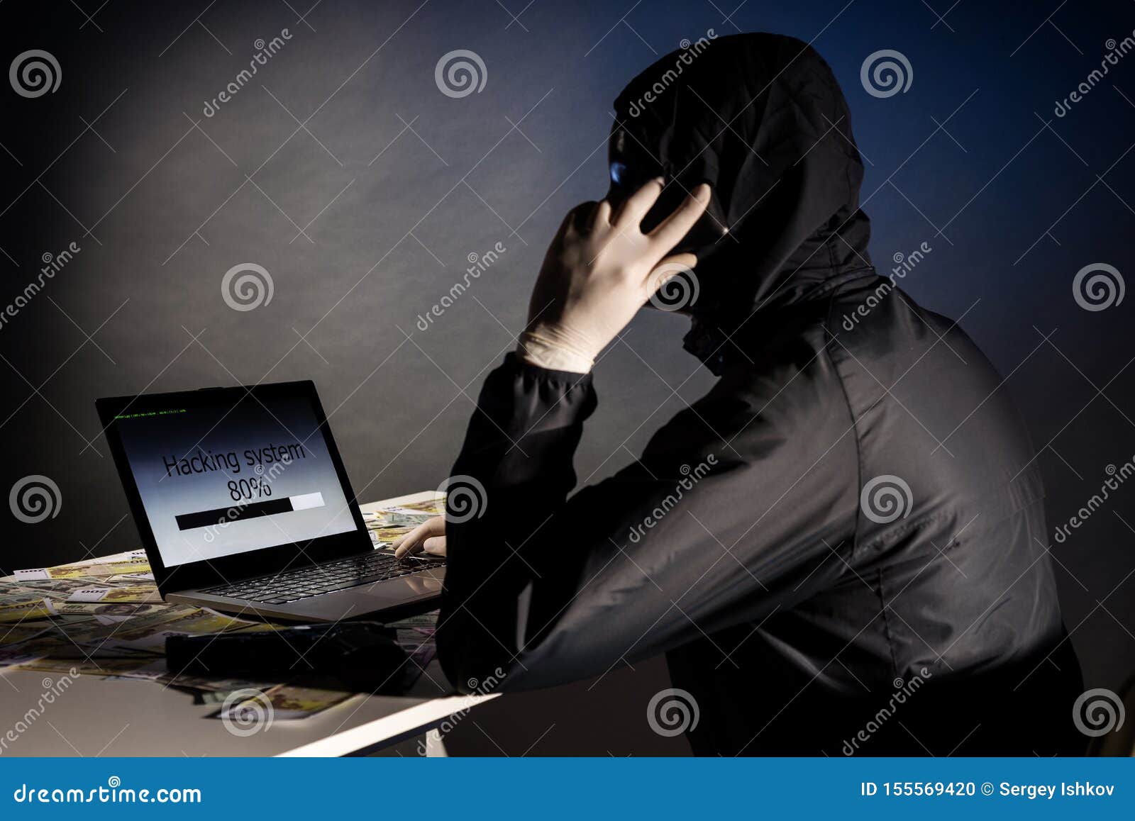 Anonymous Hacker in Mask Sitting Sideways Uses a Laptop and Talking on ...